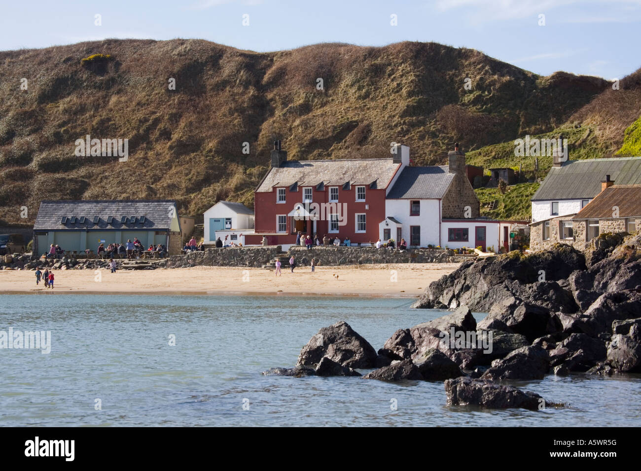 View across calm sea to Ty Coch Inn on a beach at Porth Dinllaen ...