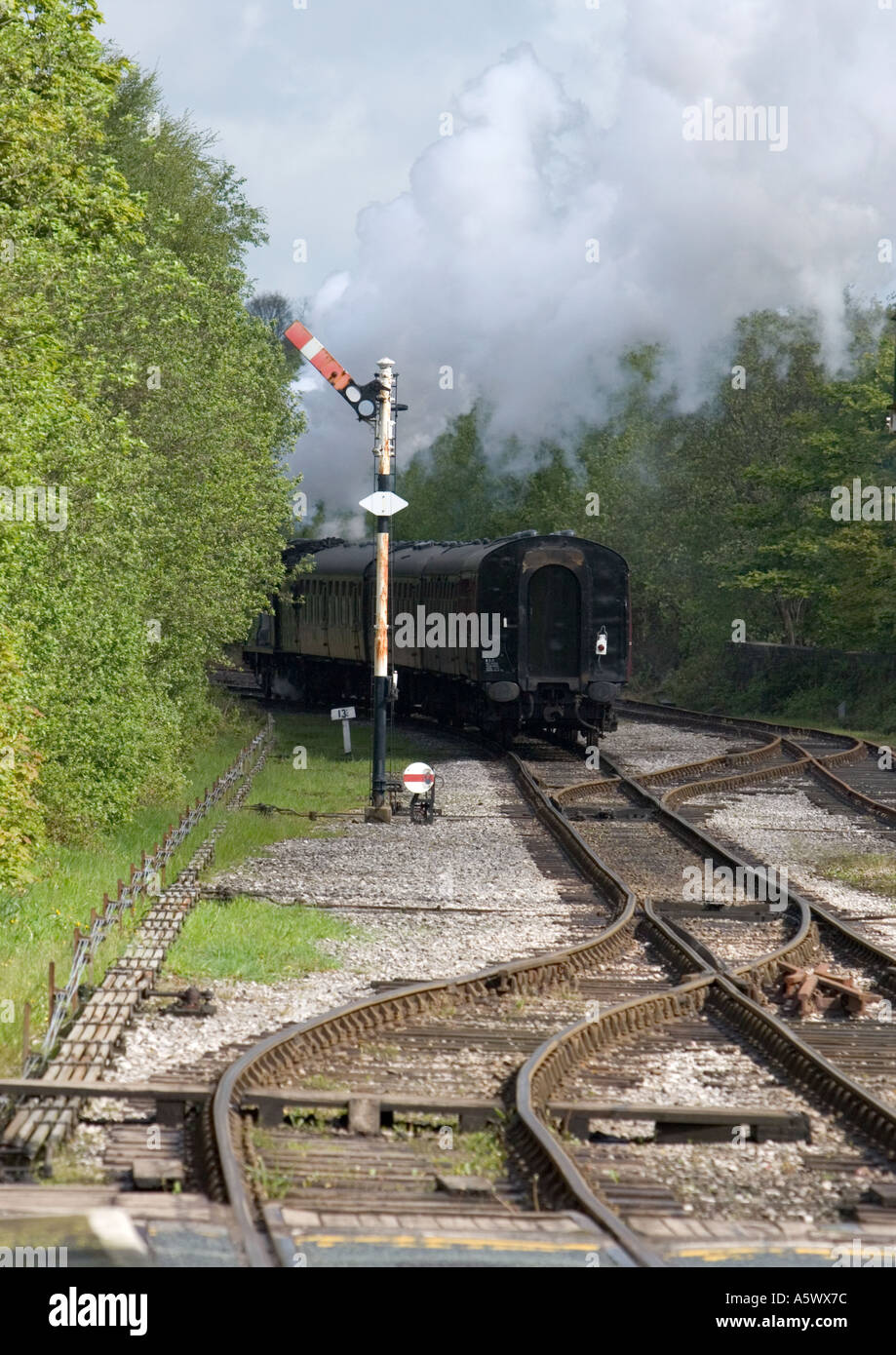 Railway points system in foreground with open signal and steam train ...