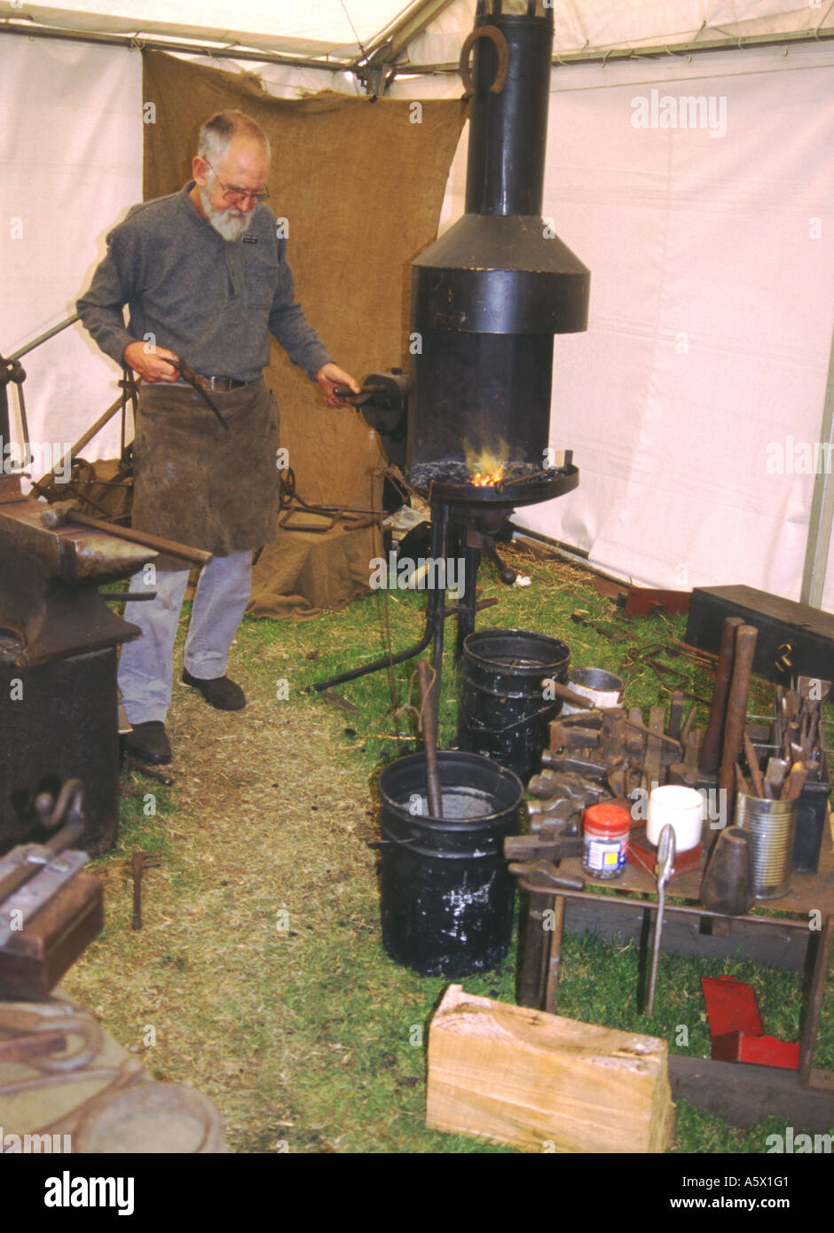 A blacksmith fires up the coal forge Stock Photo - Alamy