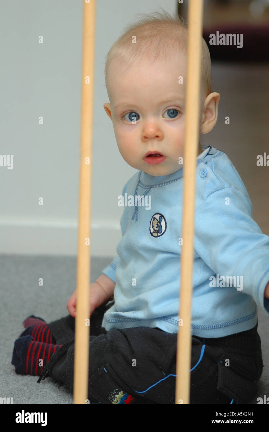 Baby behind safety gate Stock Photo - Alamy
