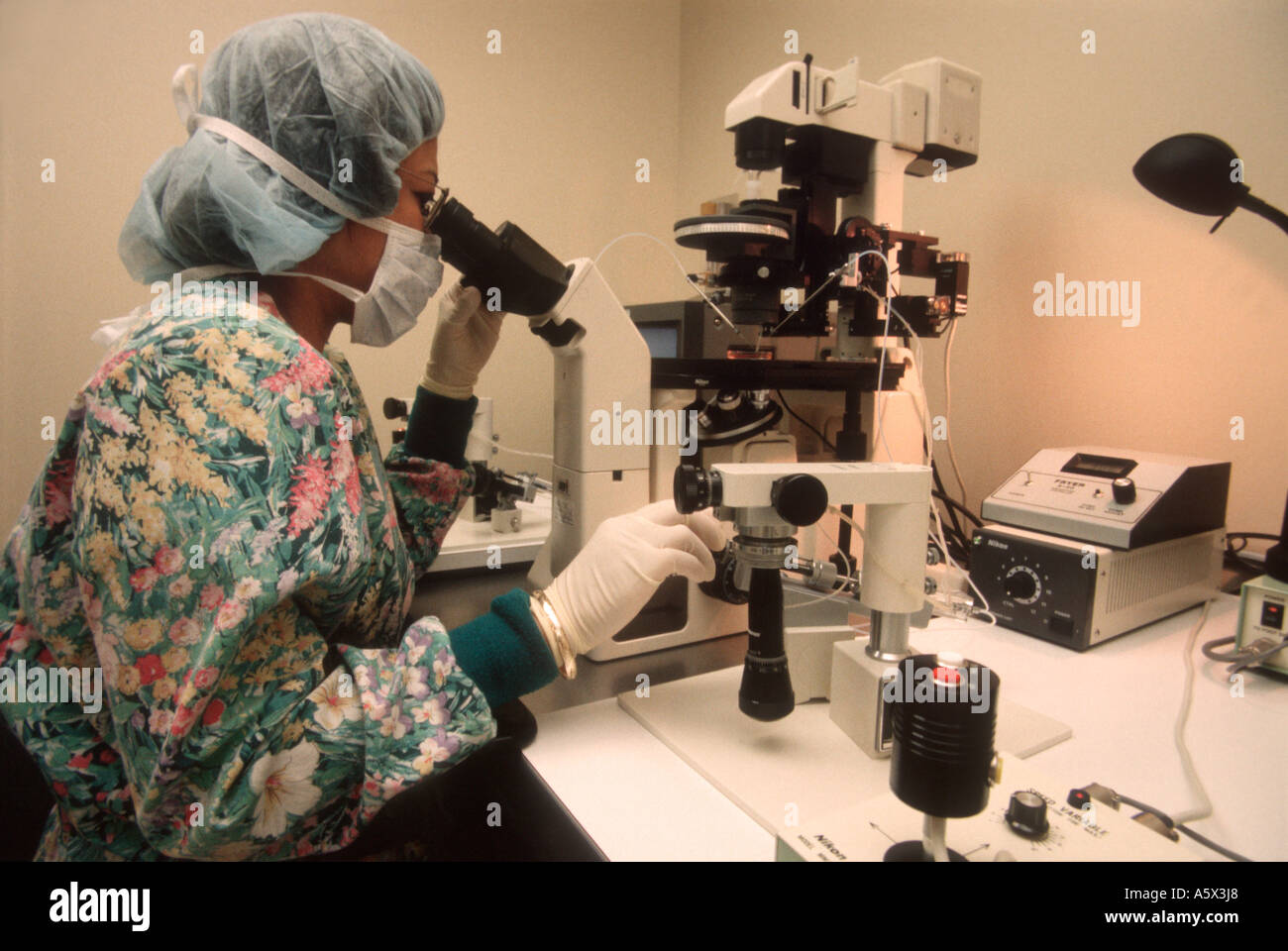 a laboratory technician at a fertility clinic looks through a ...
