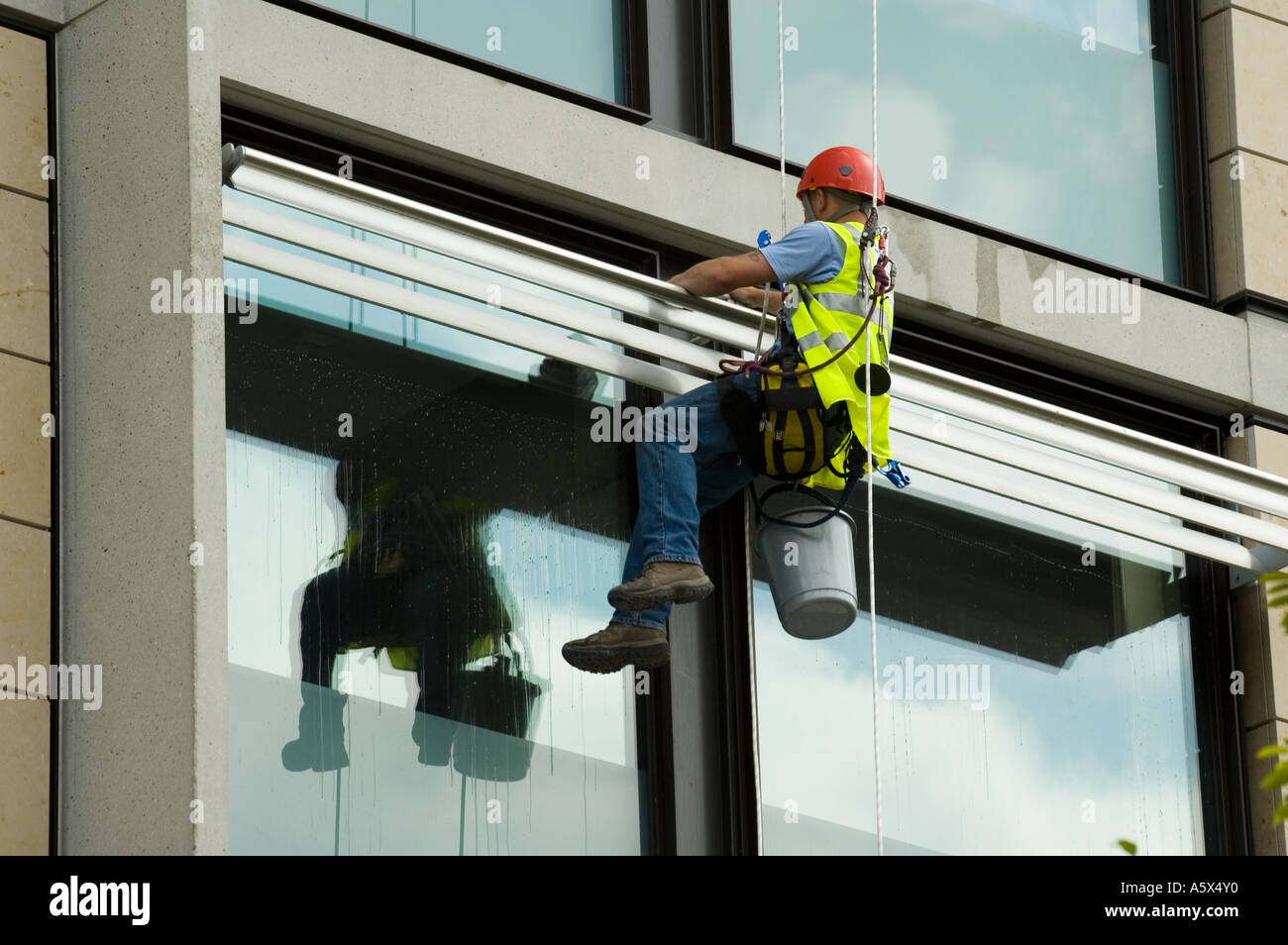 Window cleaner using industrial rope access techniques at work on a ...