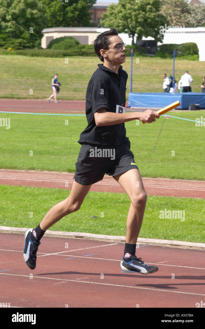 Young man on running track in relay wearing different coloured tops ...