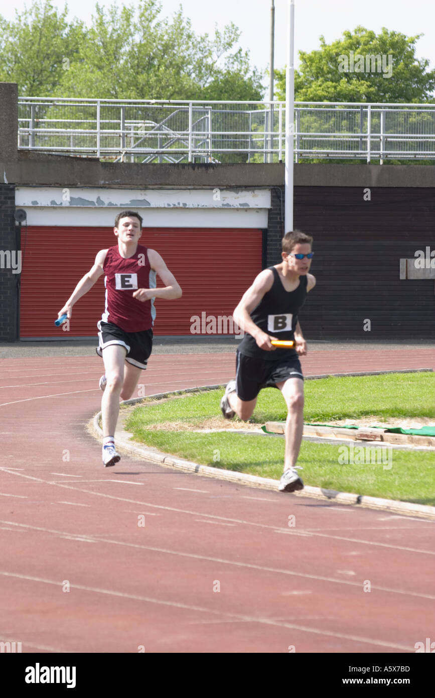 Young men on running track in relay wearing different coloured tops ...