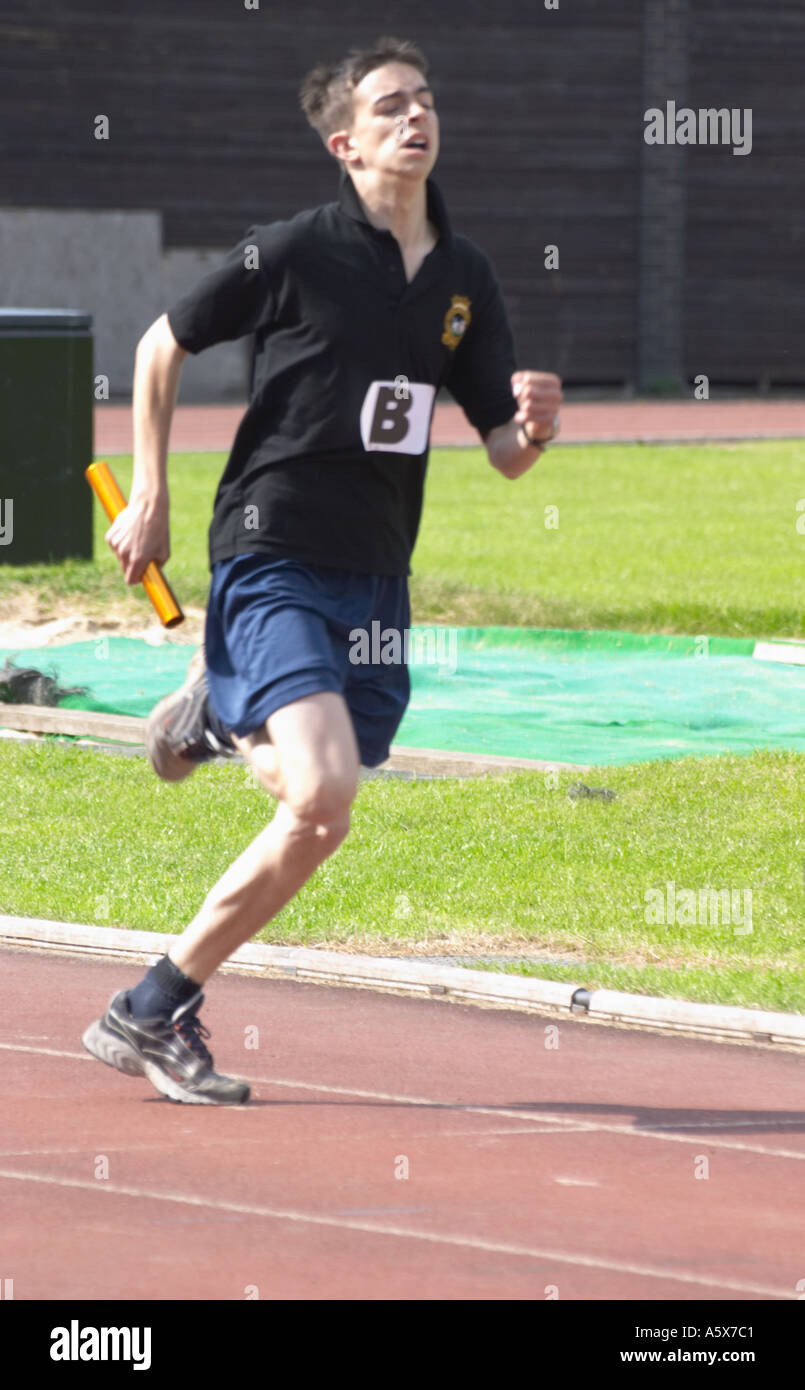 Young man on running track in relay wearing different coloured tops ...