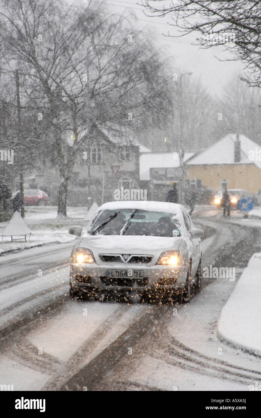 Car driving slowly to work on a snowy winters morning England Stock ...