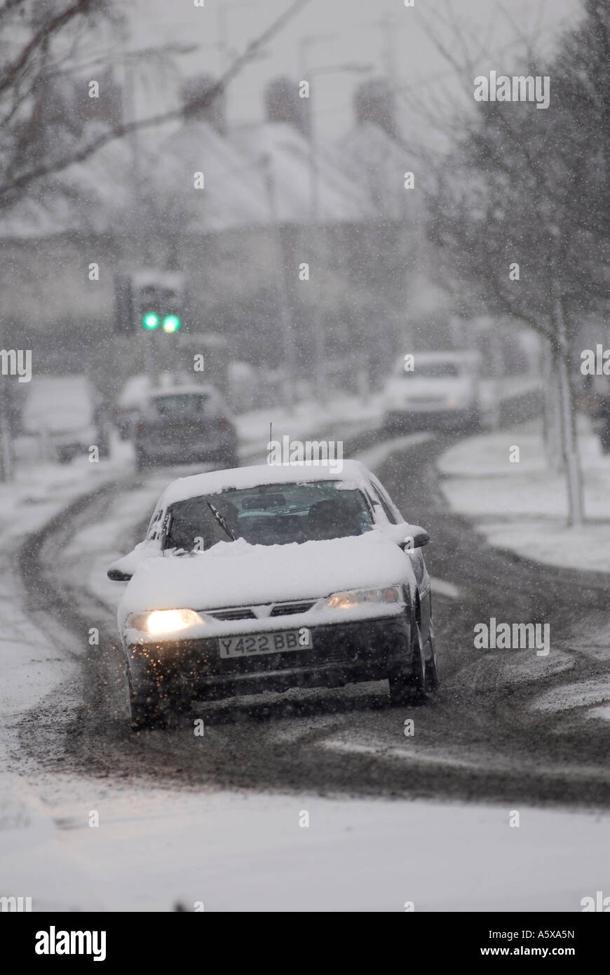 Car sliding along on a slushy road on a snowy winters morning England ...