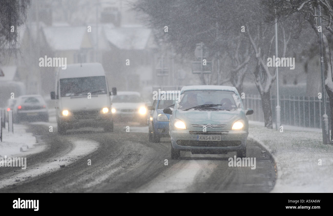 Traffic driving slowly to work on a snowy winters morning England Stock ...