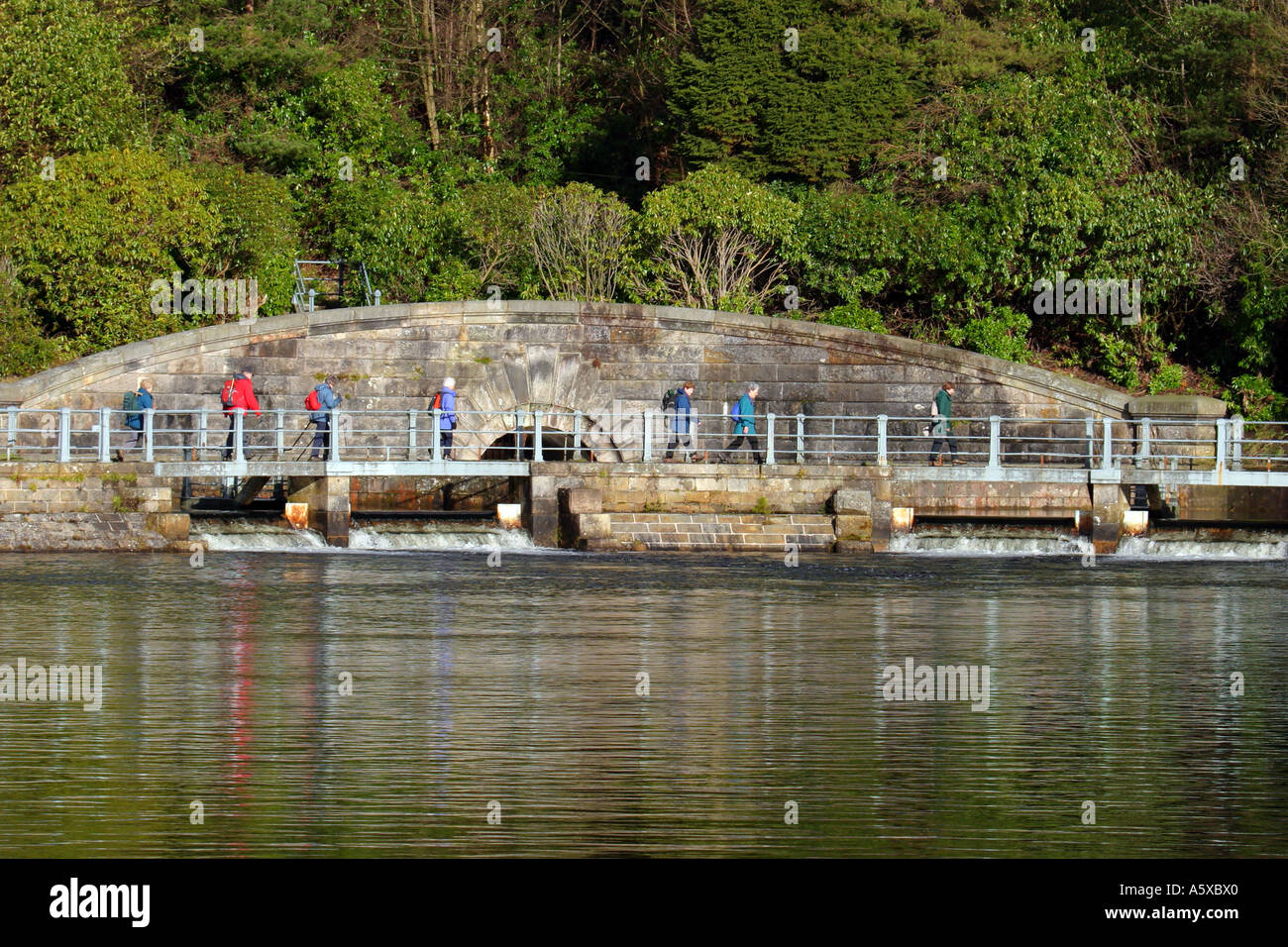 Walkers crossing a footbridge over a reservoir inlet, Milngavie Stock ...