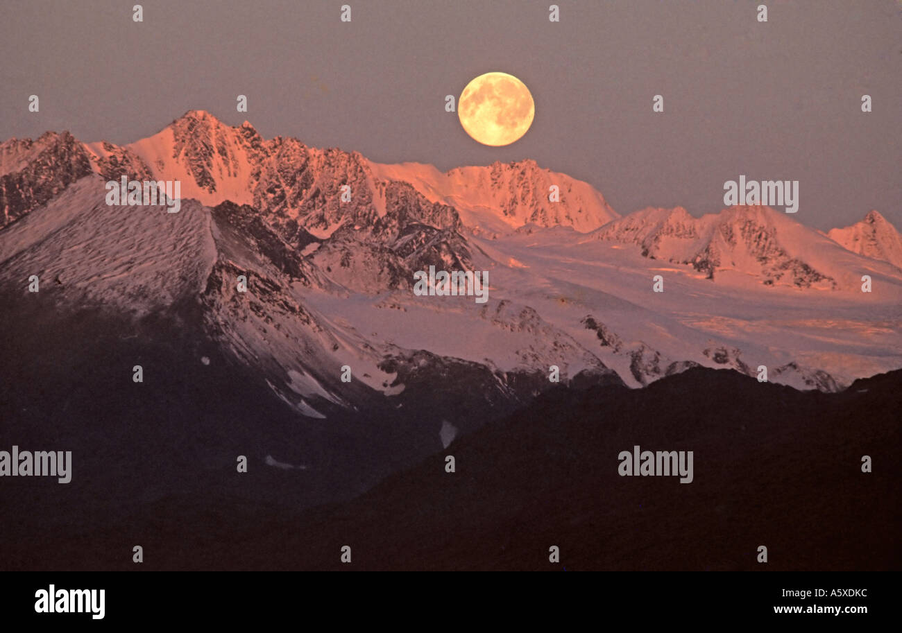 Alaska full moon over snow capped mountain range Stock Photo - Alamy