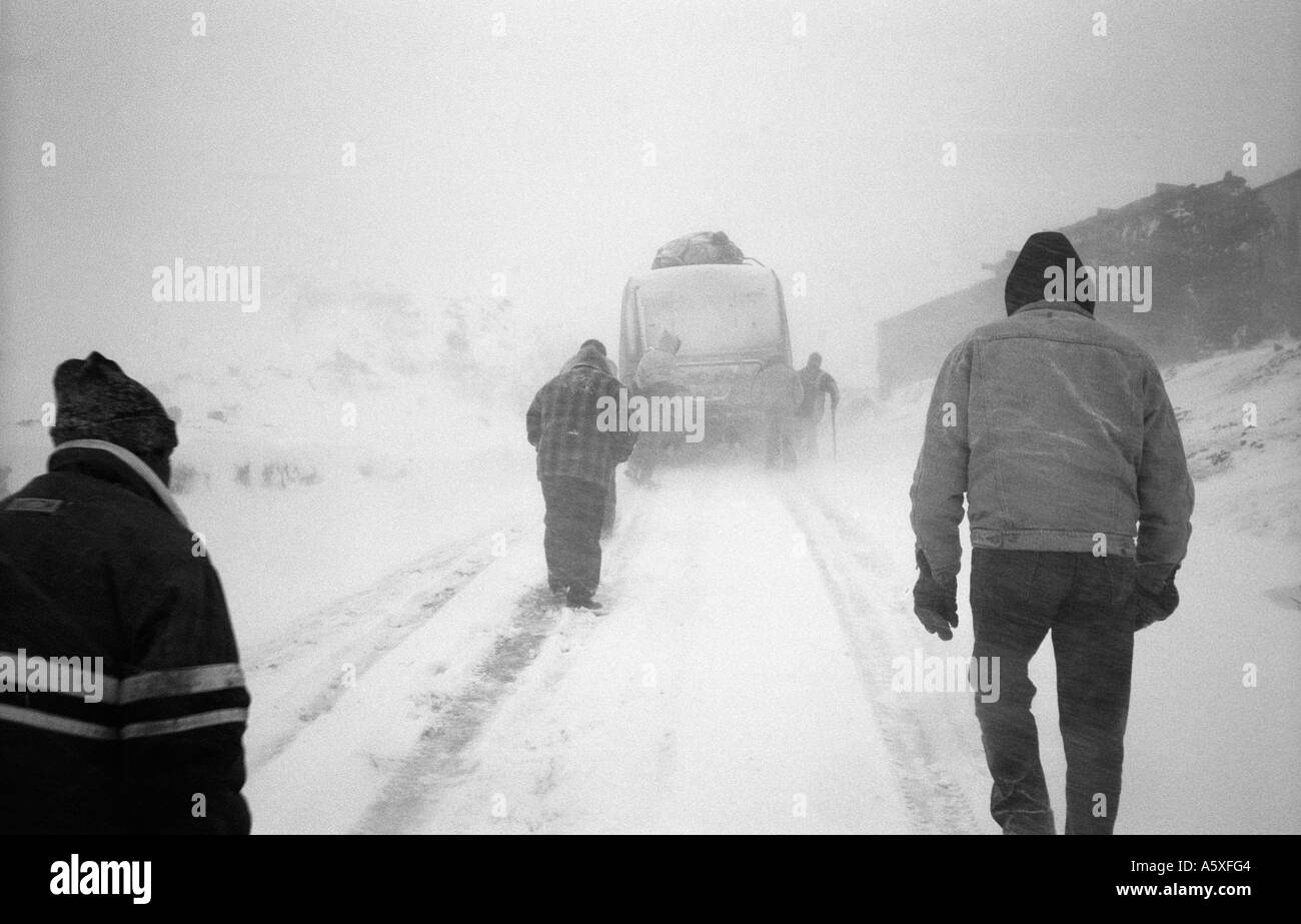 People walking through snow and going to help push the bus stranded in ...
