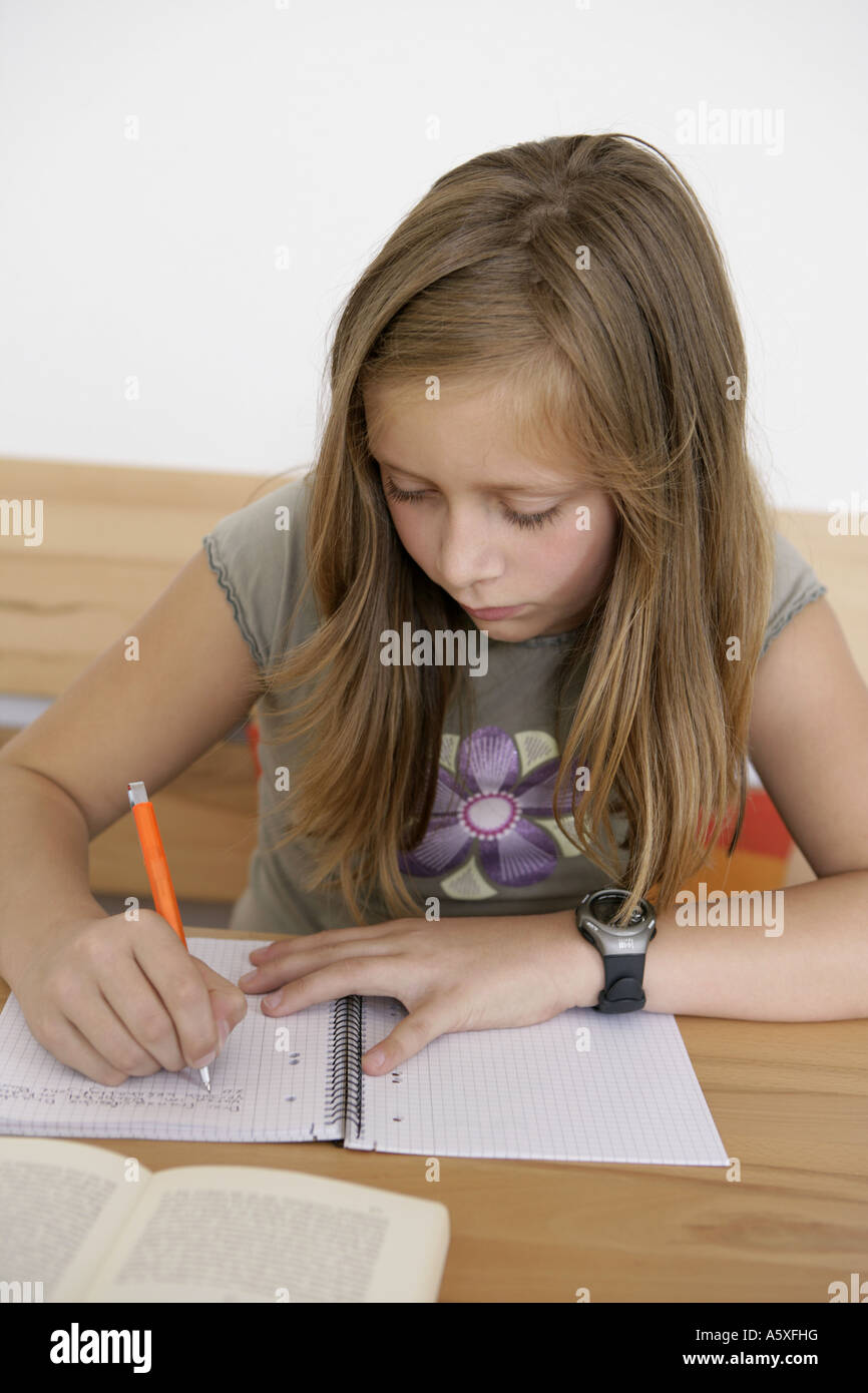 Girl sitting at desk doing homework portrait Stock Photo - Alamy
