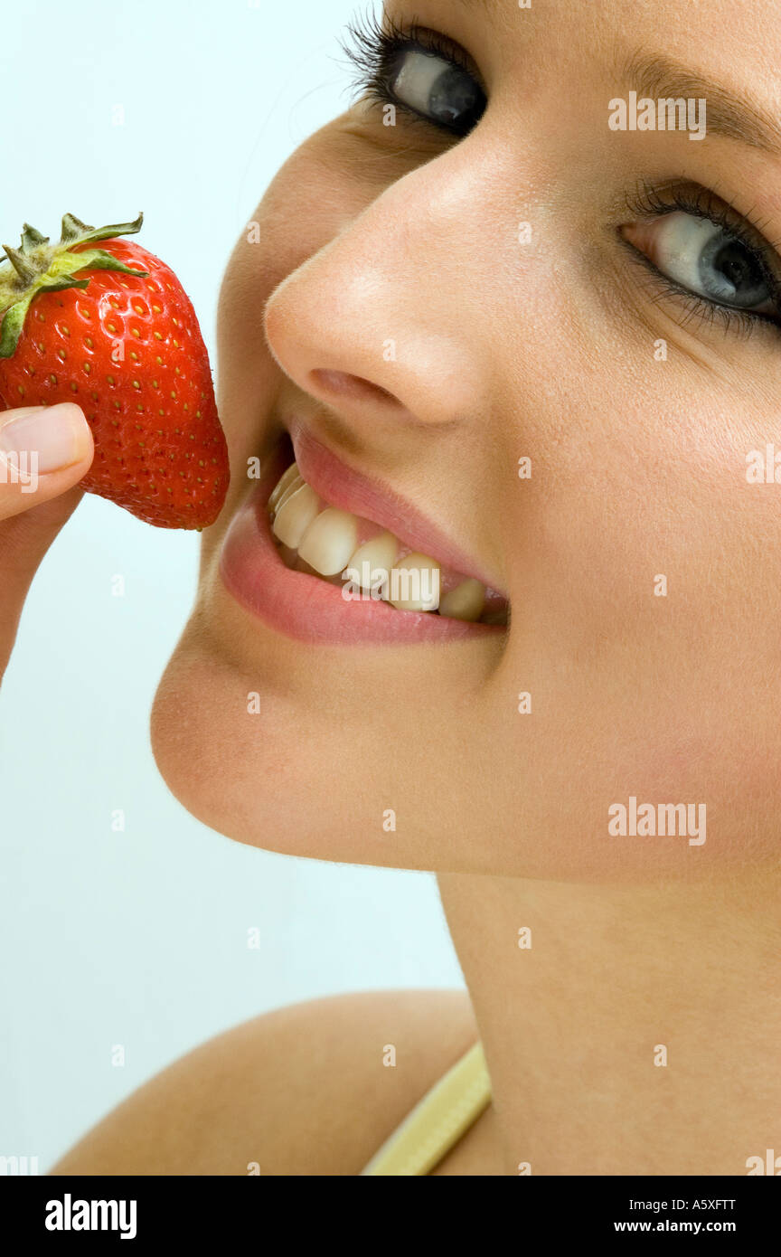 Young woman holding strawberry smiling close up portrait Stock Photo ...