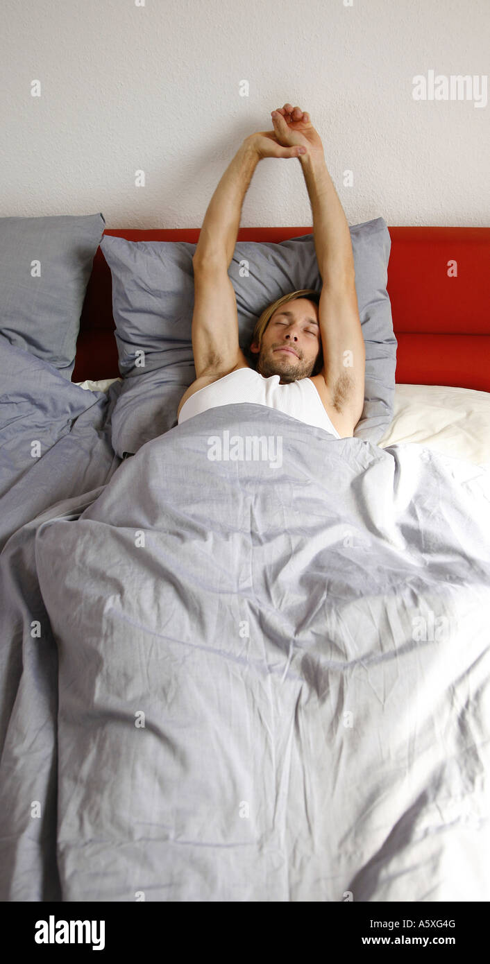 Young man stretching lying on bed elevated view Stock Photo - Alamy