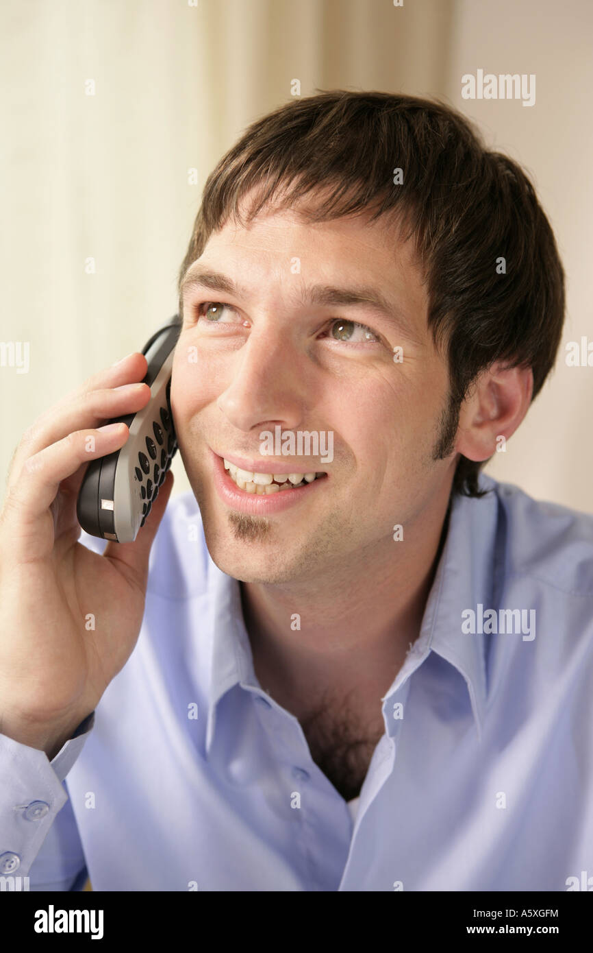 Young man using cordless phone smiling close up Stock Photo - Alamy
