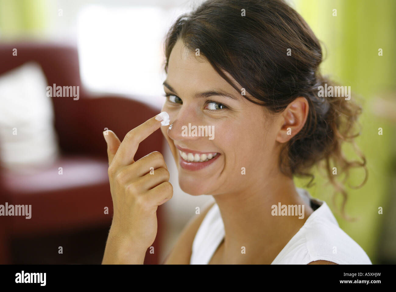 Young woman applying lotion on her face smiling portrait Stock Photo ...