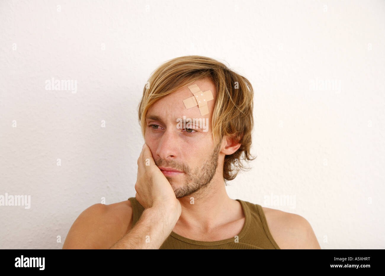 Young man with plaster on forehead hand on face portrait close up Stock ...