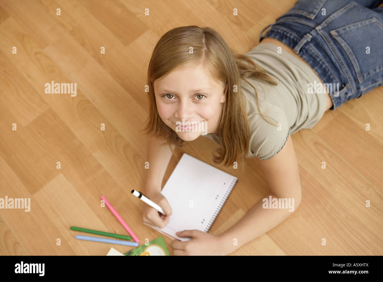 Girl 11 lying on floor writing in book portrait overhead view smiling ...