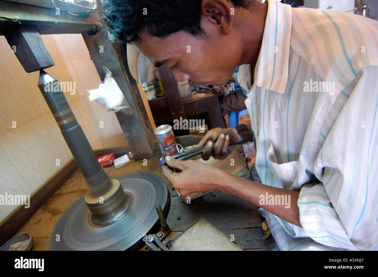 A worker polishing rough gemstone in a shop in Banlung, a town in the ...