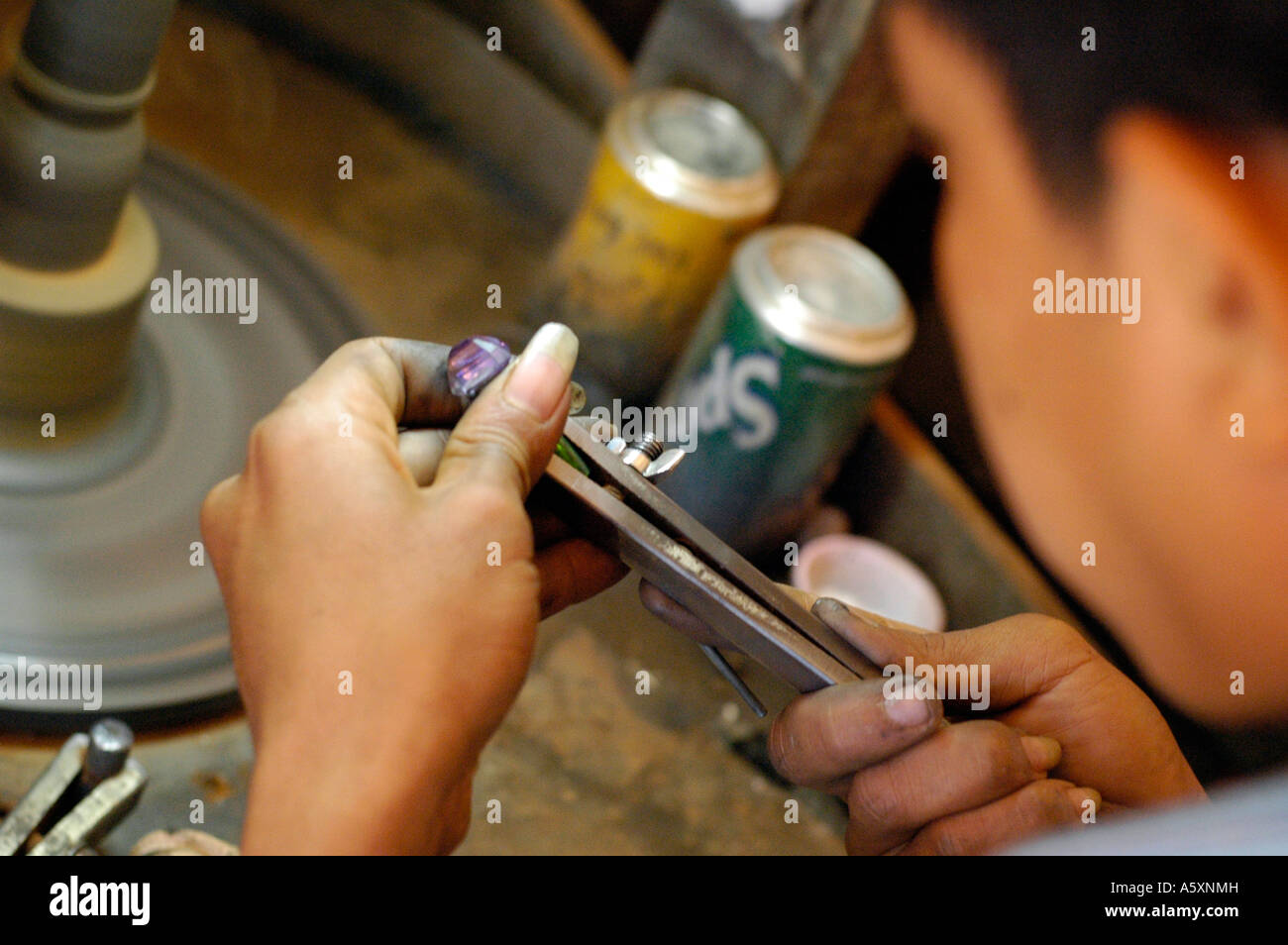 A worker polishing rough gemstone in a shop in Banlung, a town in the ...