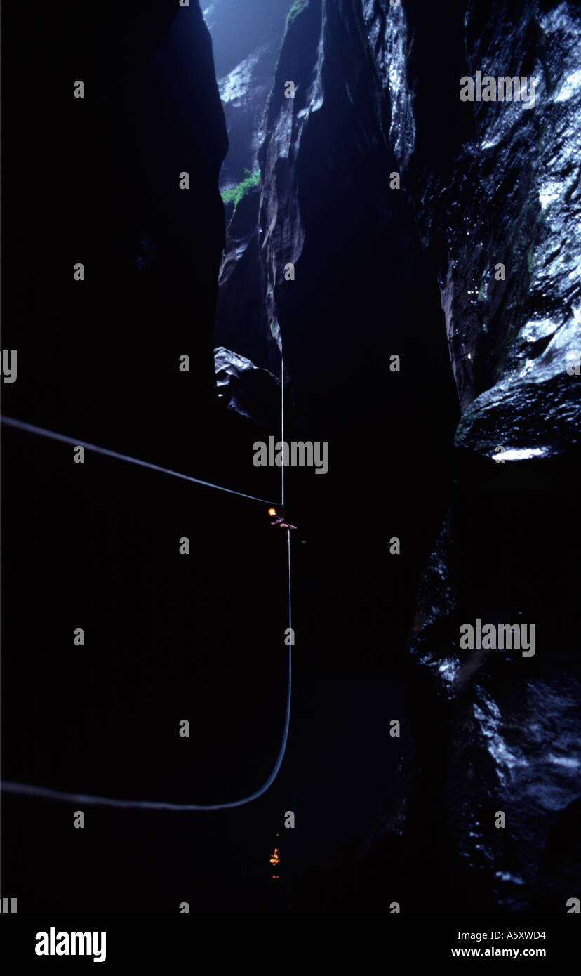 A caver uses single rope techniques to descend a pitch in a huge river ...