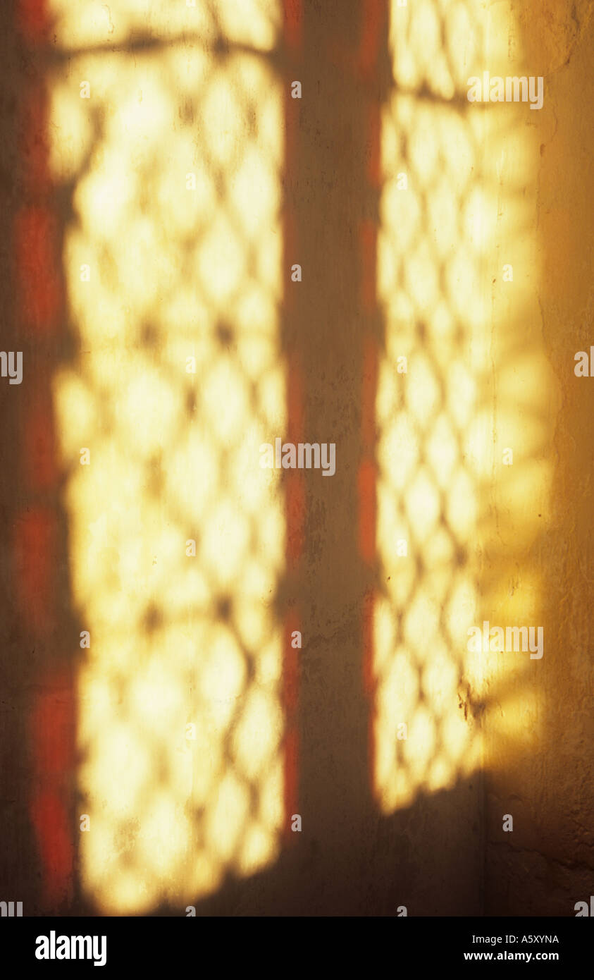 The projection in warm light of two diamond leaded windows with red ...