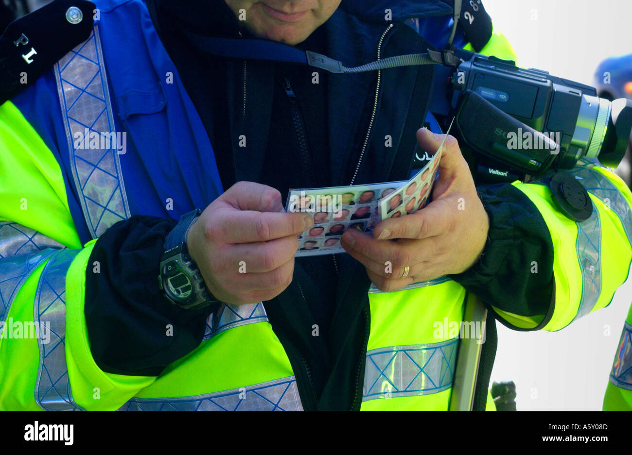 Metropolitan police spotter with video camera looking at his mug shots ...