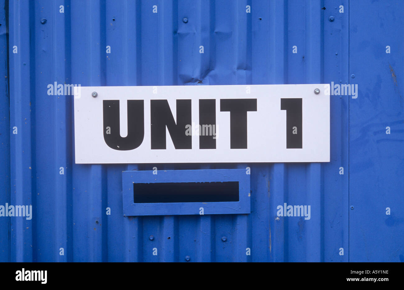 Sign above a letterbox on a blue corrugated iron fence or wall stating ...