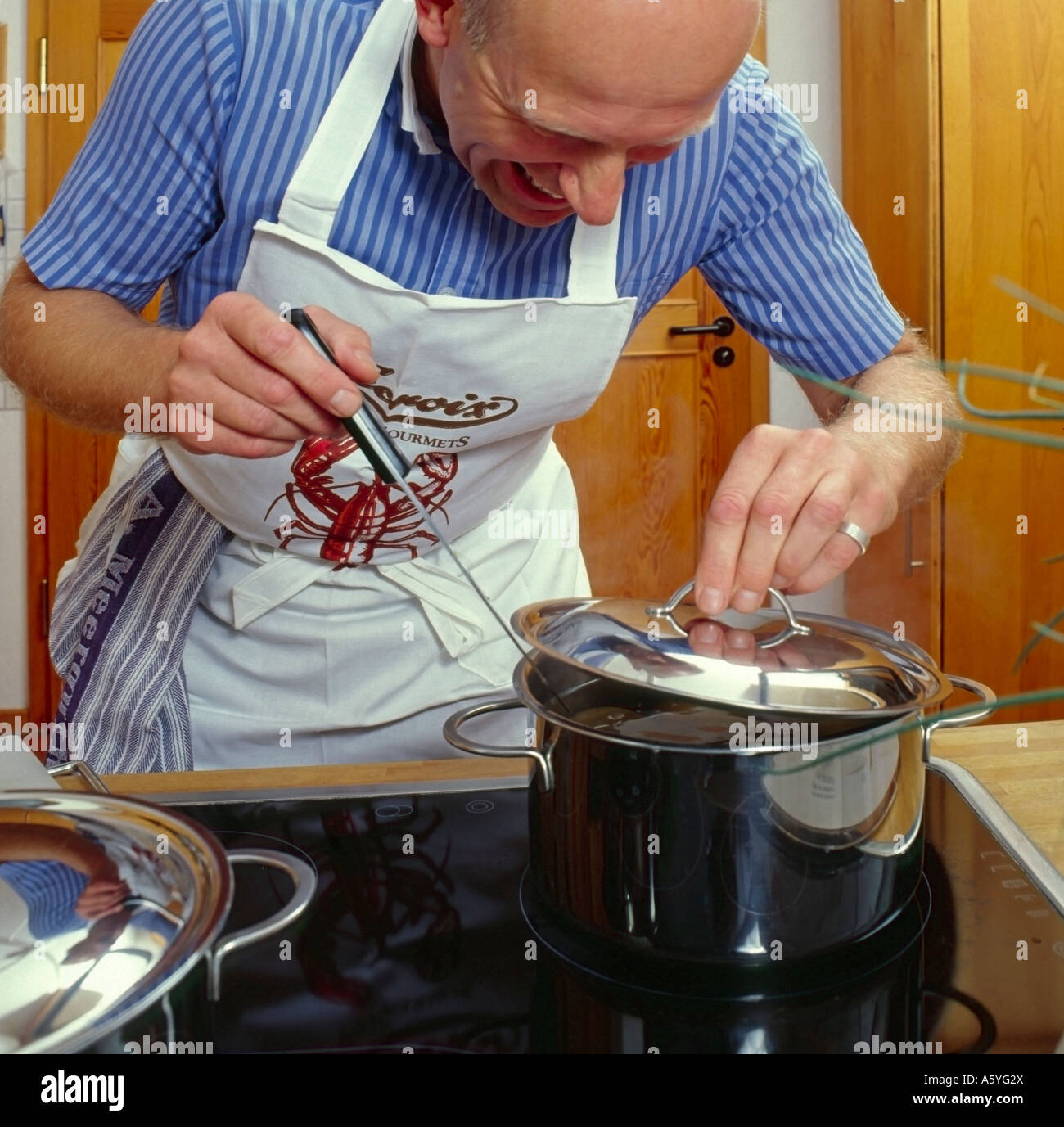 man cooking in the kitchen looking curious into a cooking pot Stock ...