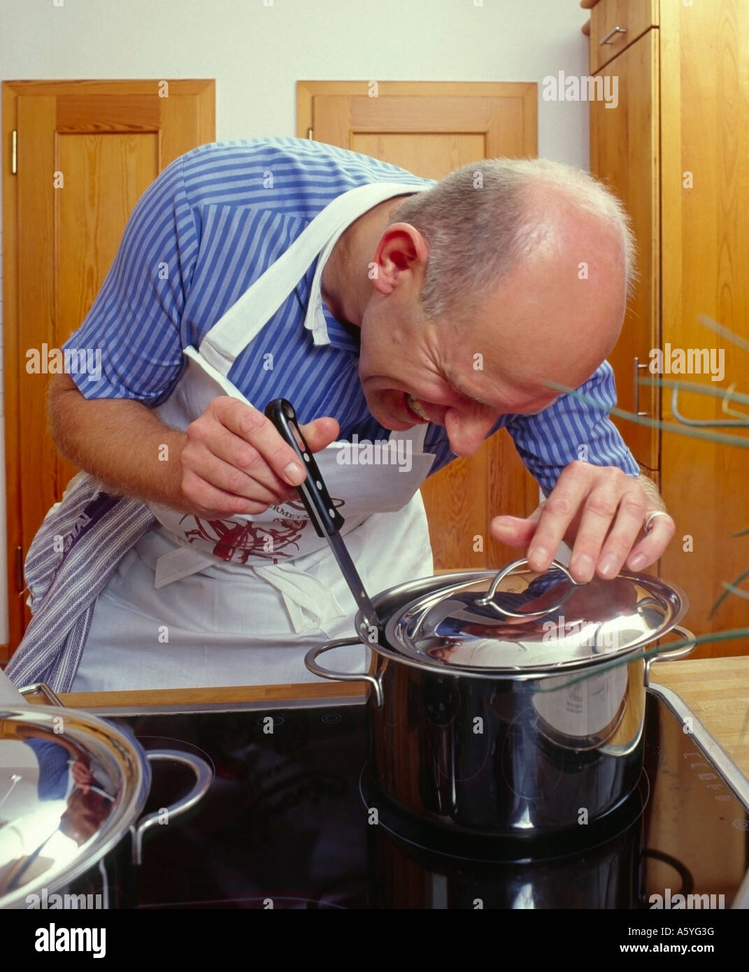 man cooking in the kitchen looking curious into a cooking pot Stock ...