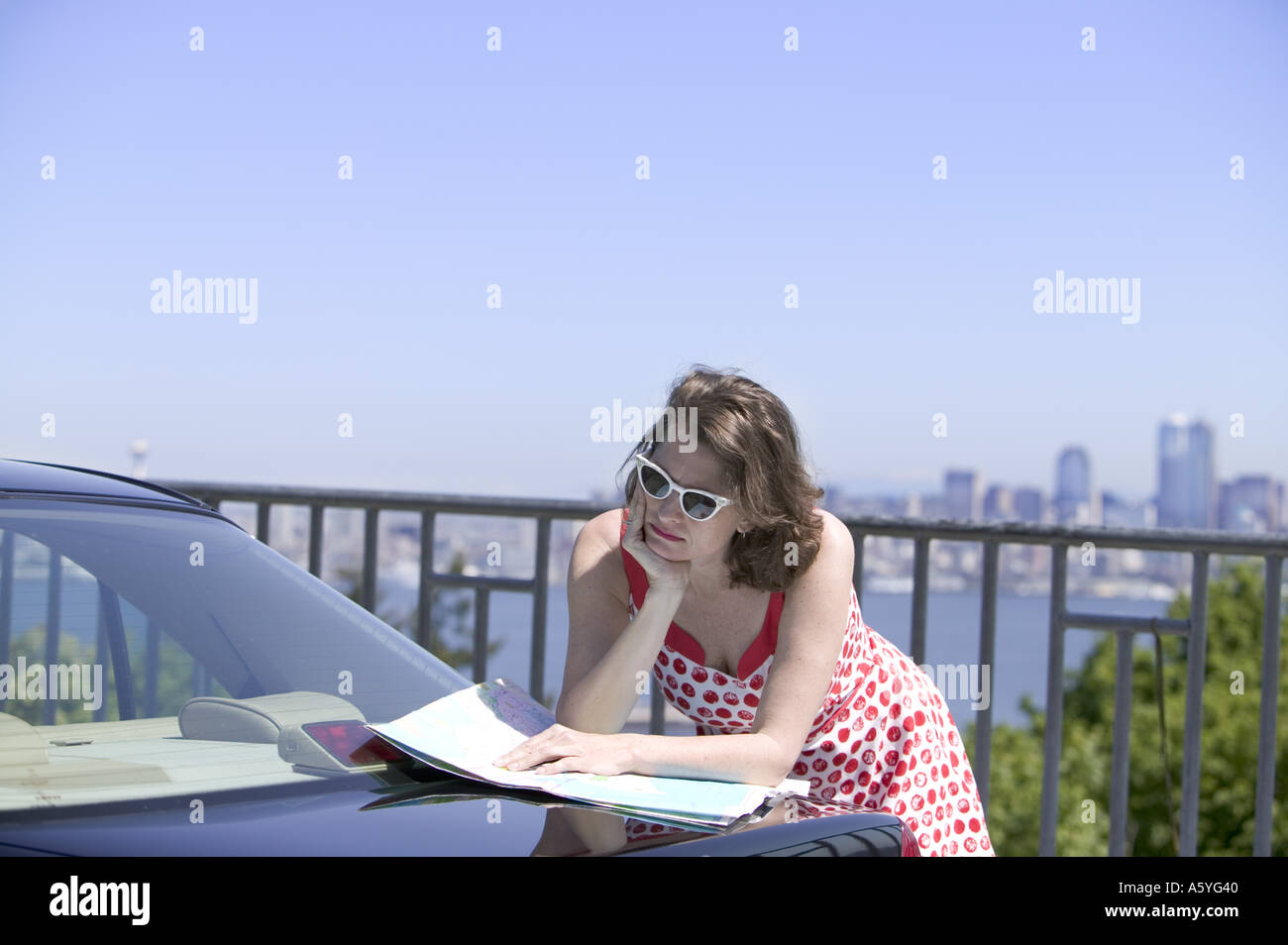 Woman leaning on car reading map Stock Photo - Alamy