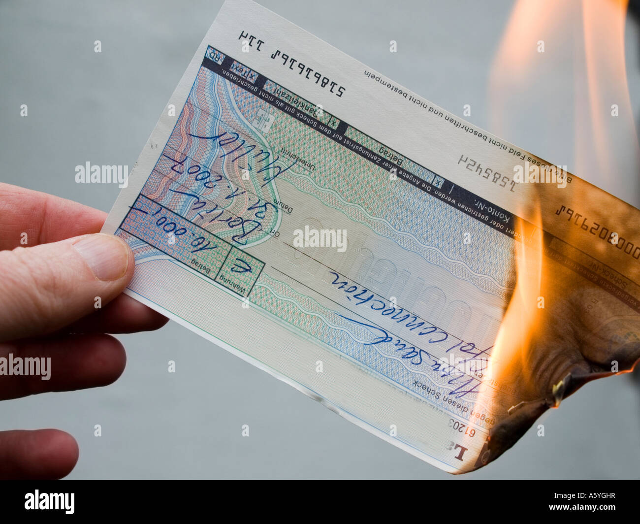 hand holding a burning cheque eurocheque Stock Photo - Alamy