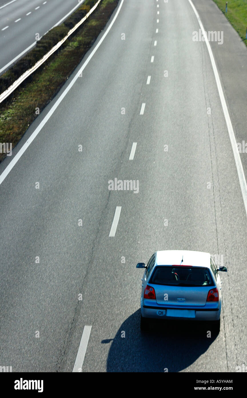 A solitary car drives away down an empty motorway (autobahn, autoroute ...