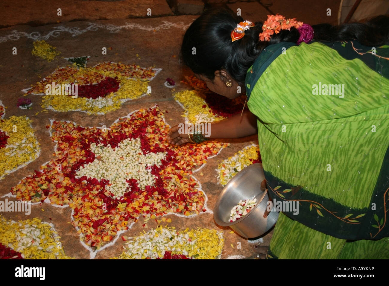 Lady making a flower rangoli pattern for the Karaga Festival ...