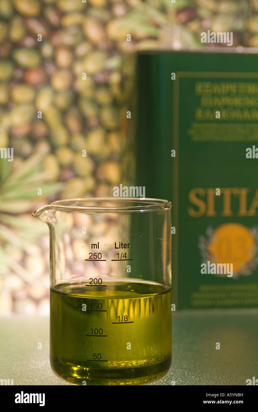 measuring jar glas filled with olive oil in the background can with ...