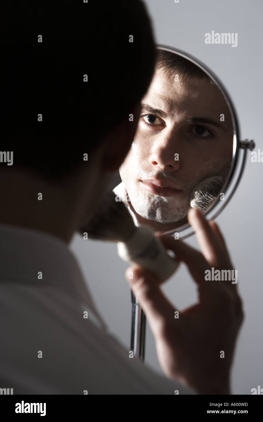 Young man shaving in mirror Stock Photo - Alamy