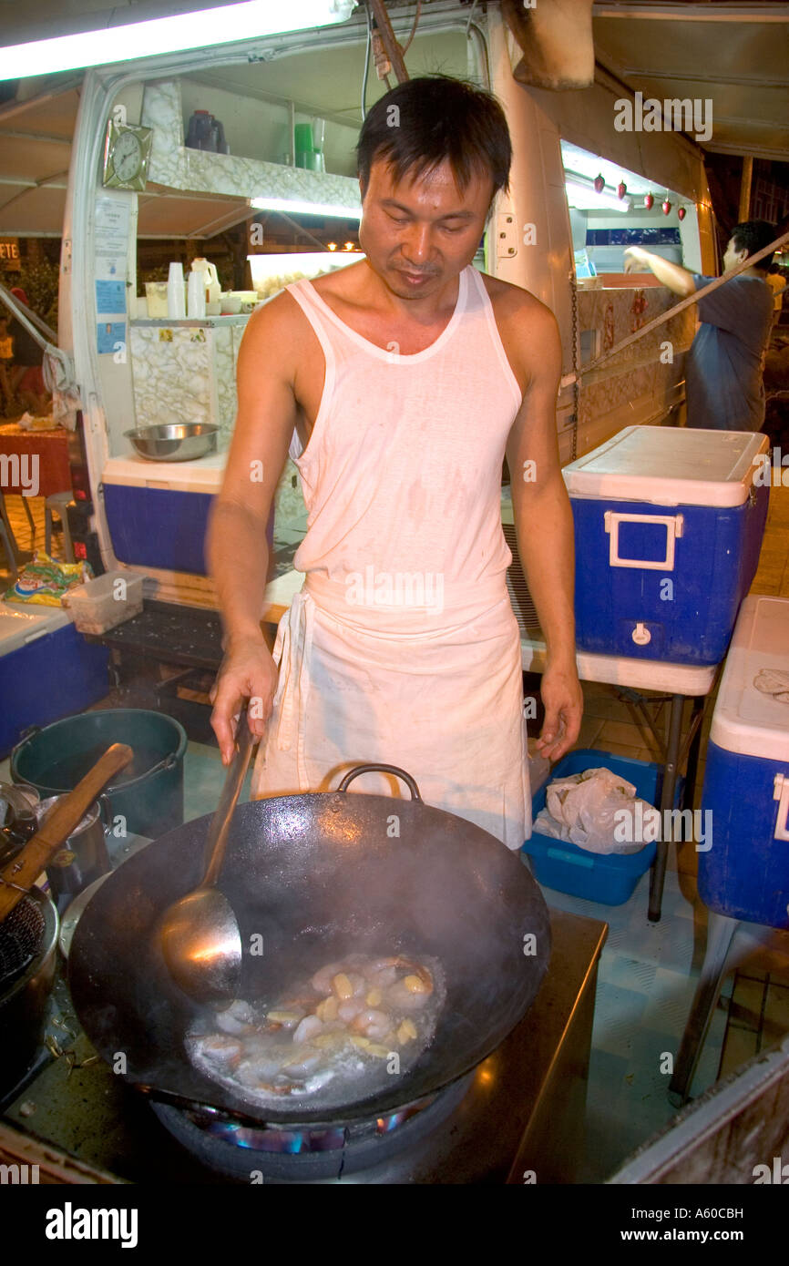Chinese man cooking with a wok at a roulotte food van in Papeete on the ...