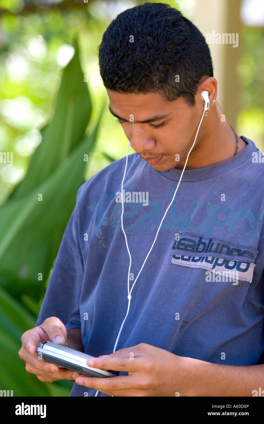 Teenage boy listening with head phones to a cd player on the island of ...