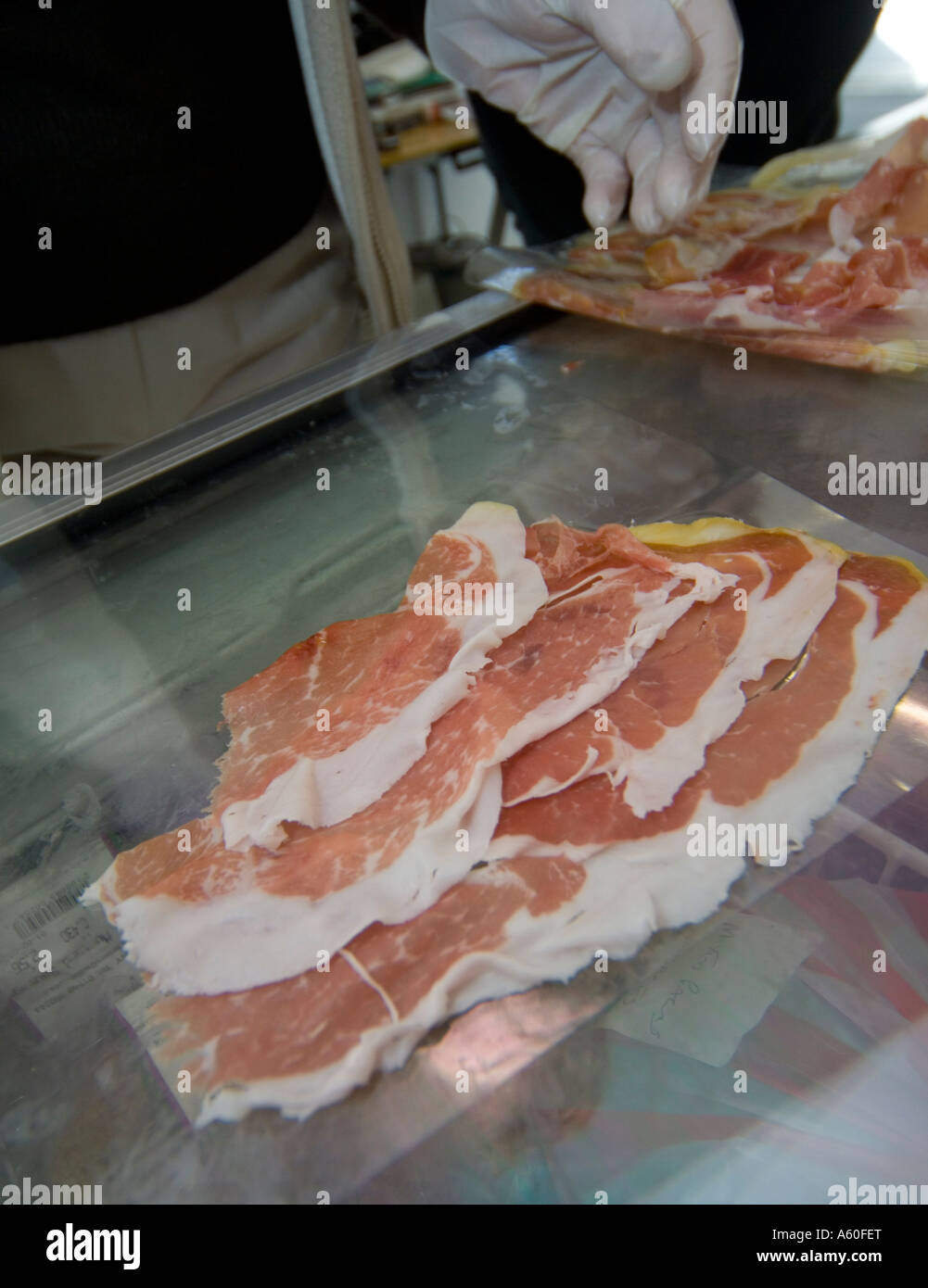 A woman's hands packing freshly cut prosciutto Crudo, parma ham, into ...