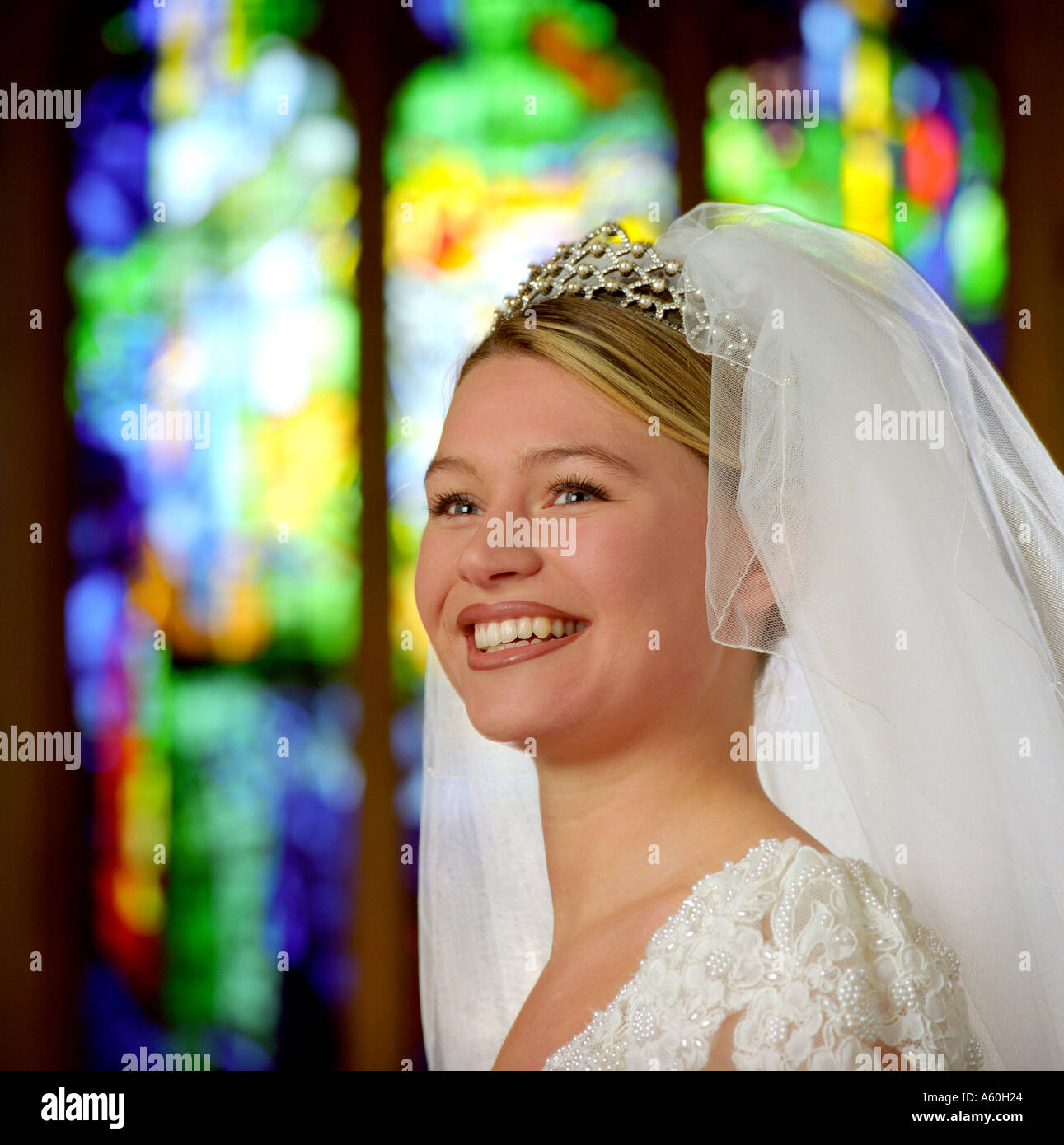 Bride smiling inside church with stained glass window behind Stock ...