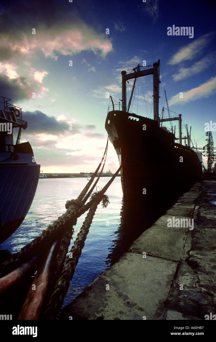 Cargo ship discharging its load at quayside at sunset Stock Photo - Alamy