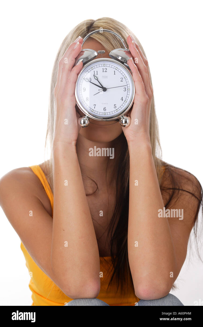 blond model hiding her face behind alarm clock Stock Photo - Alamy