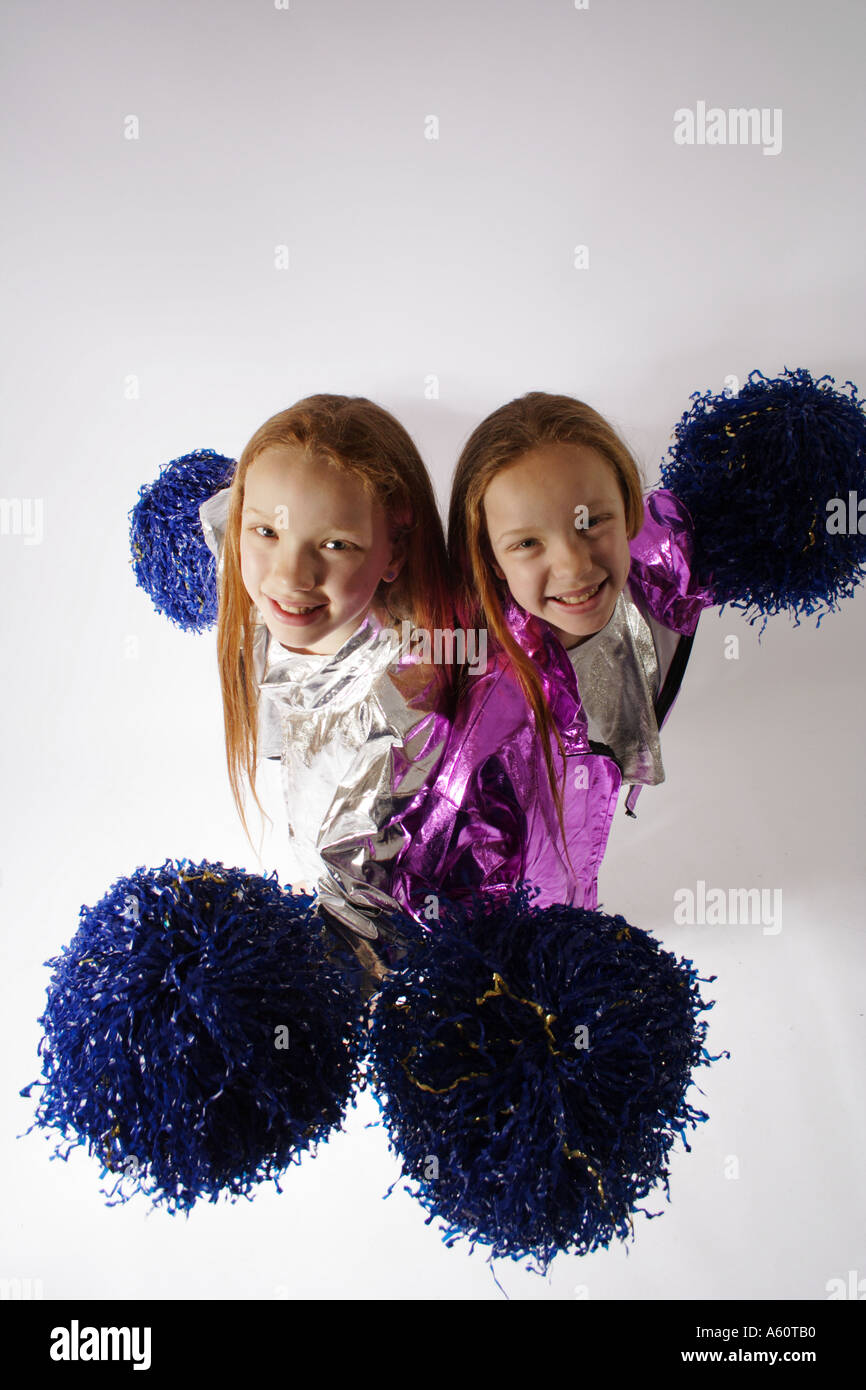 Twin sisters age 10 entertaining with pom poms look up to the camera ...