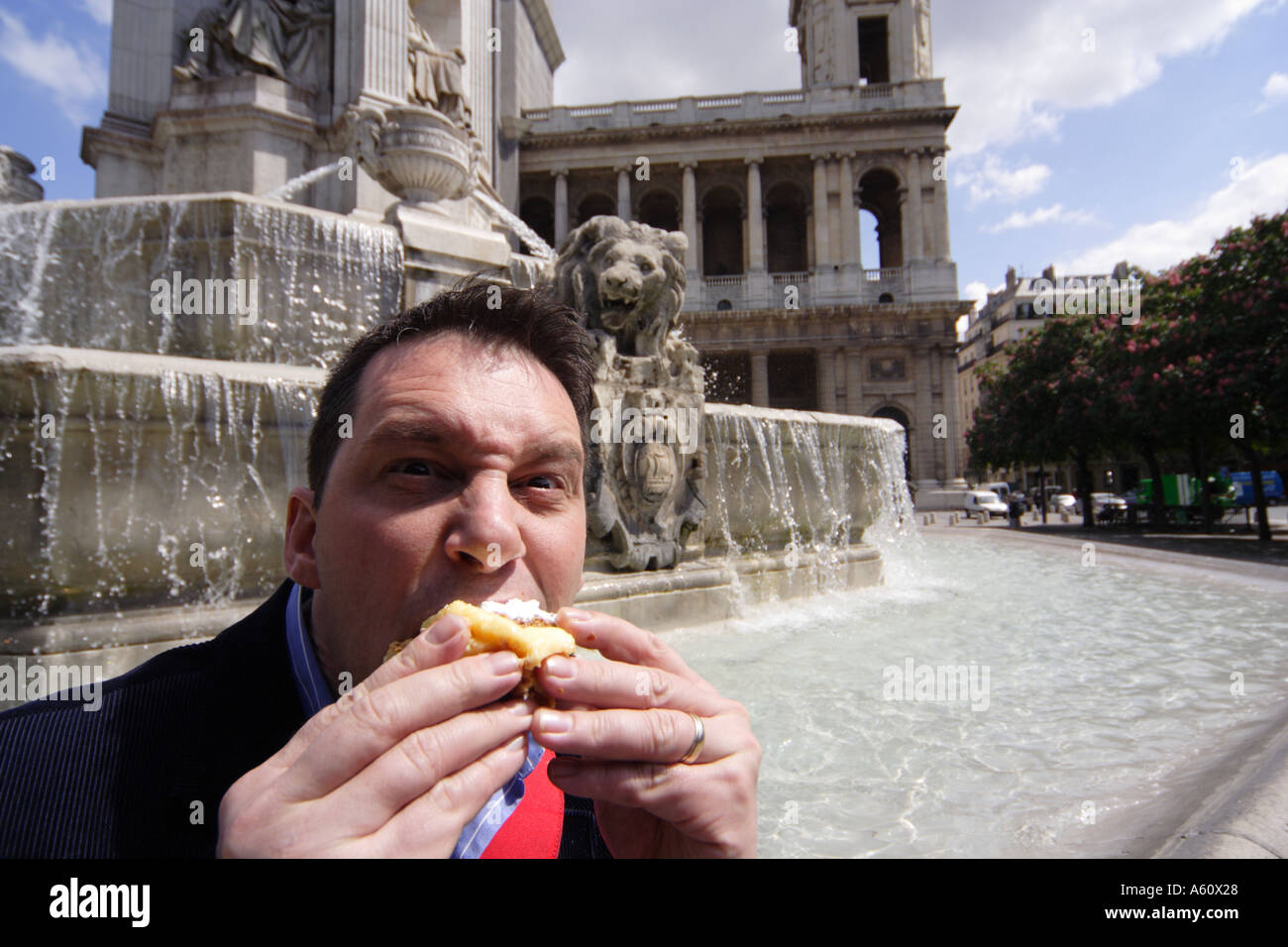 Man gorging on a cake in front of an outdoors fountain in Place Saint ...