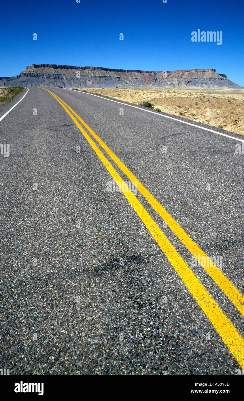 Yellow center line stripe of a desert road with a Butte on the horizon ...