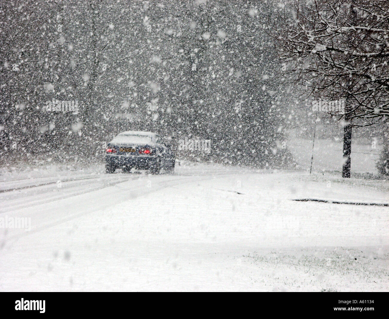 Falling snow back rear view of car driving in icy conditions covering ...