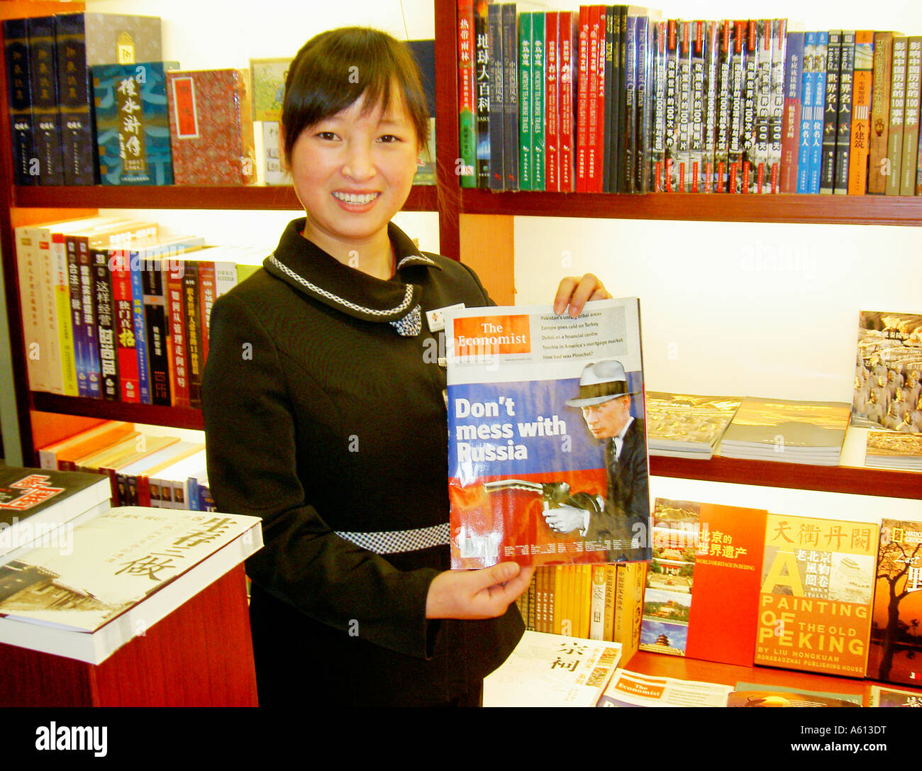 Book shop news stand sales assistant holding The Economist magazine ...
