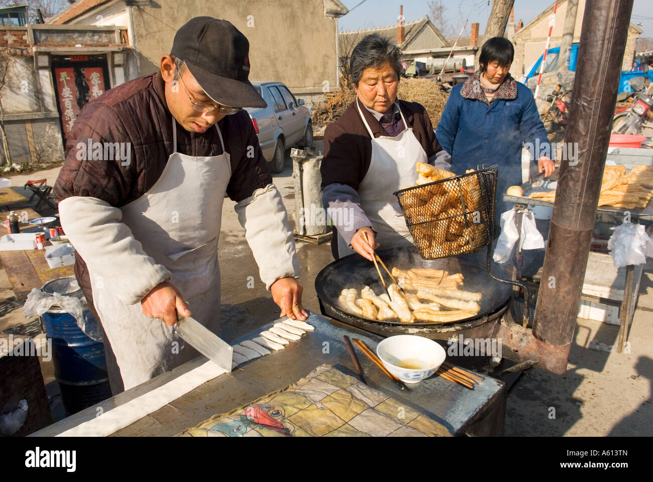 Chinese baker bread maker cutting strips of dough and cooking frying ...