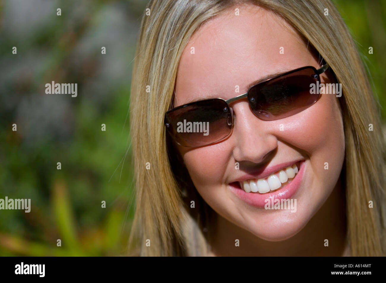A beautiful young blonde woman smiling while out in the sunshine ...