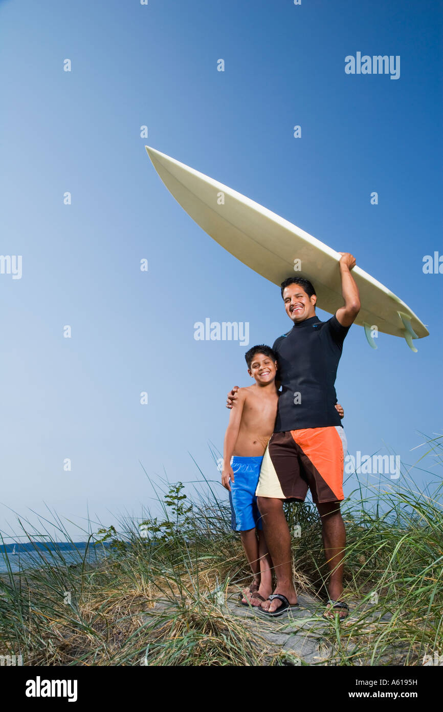 Hispanic father and son holding surfboard on beach Stock Photo - Alamy